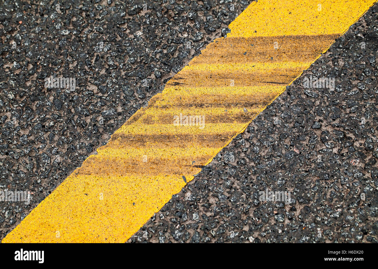 Yellow dividing line with tire tracks over it, highway road marking ...