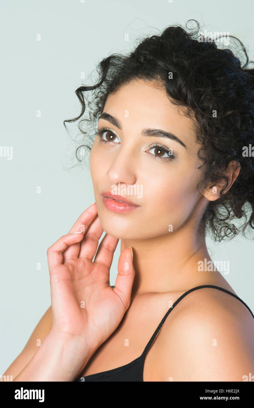 Pensive young woman looking away hand touching face Stock Photo - Alamy