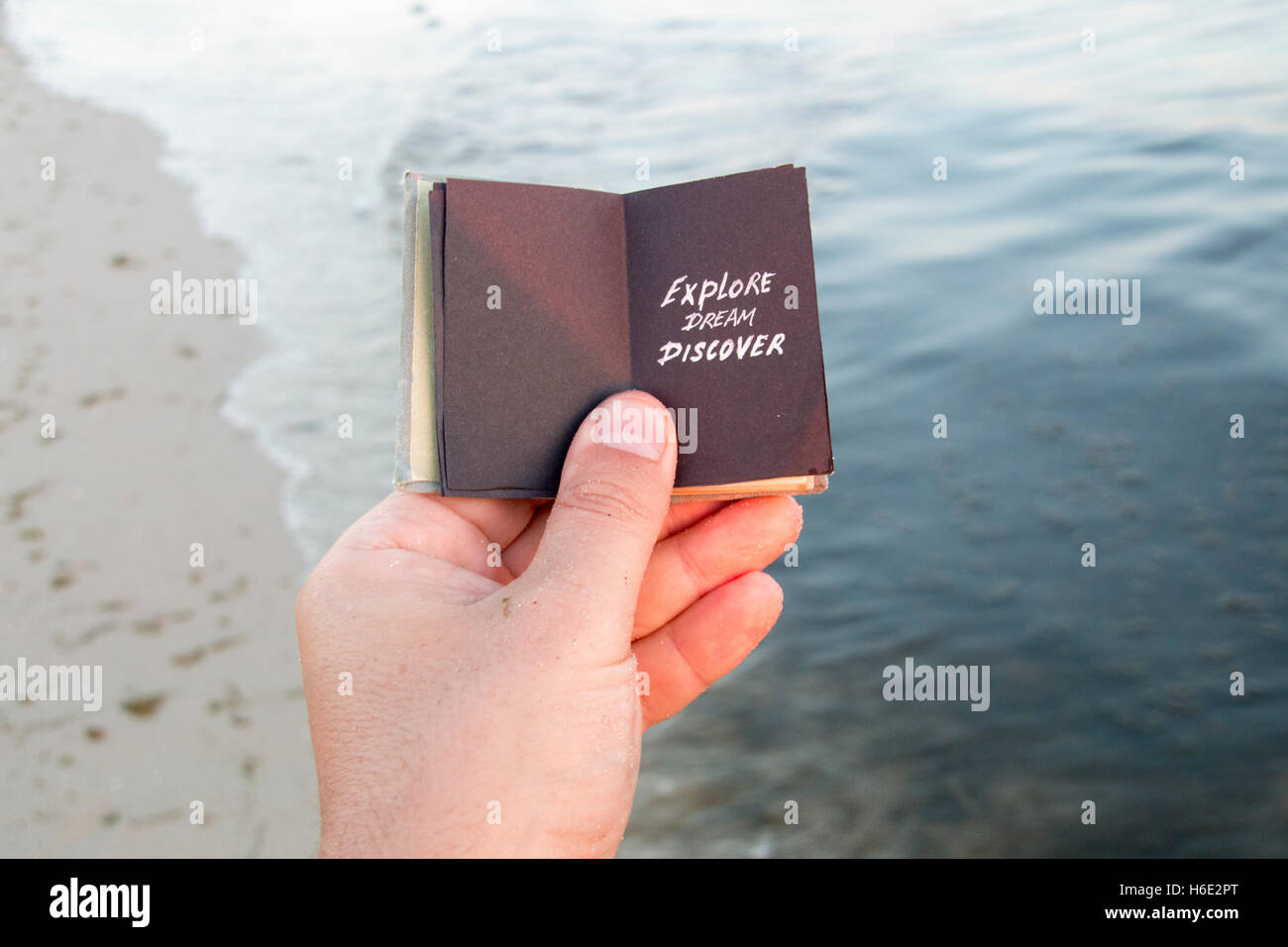 Explore Dream Discover. Book, inscription, and sandy beach Stock Photo ...