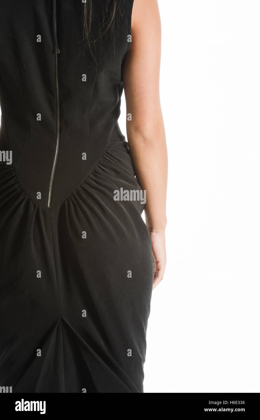Rear view of a woman wearing a black dress standing against a white ...