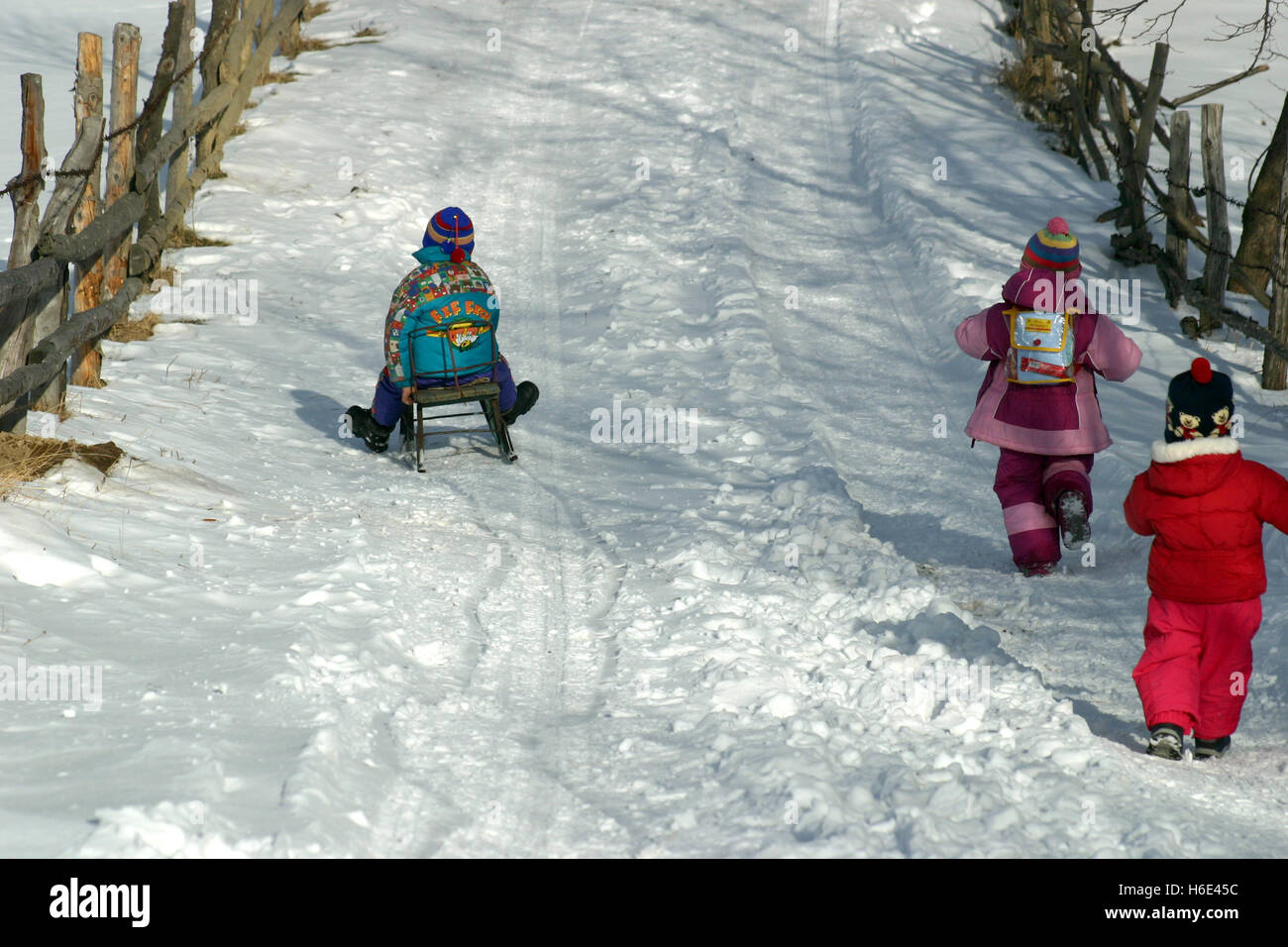 Little kids with sled walking and playing on snow in the countryside ...