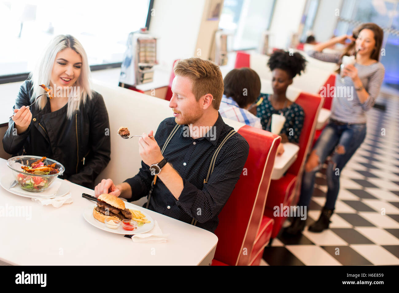 Friends eating fast food at the table in the diner Stock Photo - Alamy