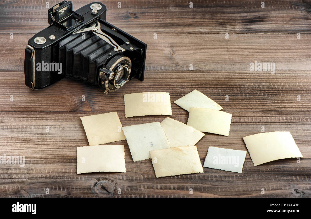 Vintage photo camera and old paper photos on wooden table. Memories ...