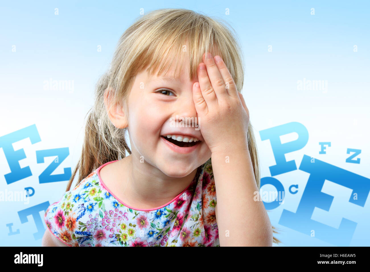 Close up fun portrait of little girl closing on eye with hand.Big block ...