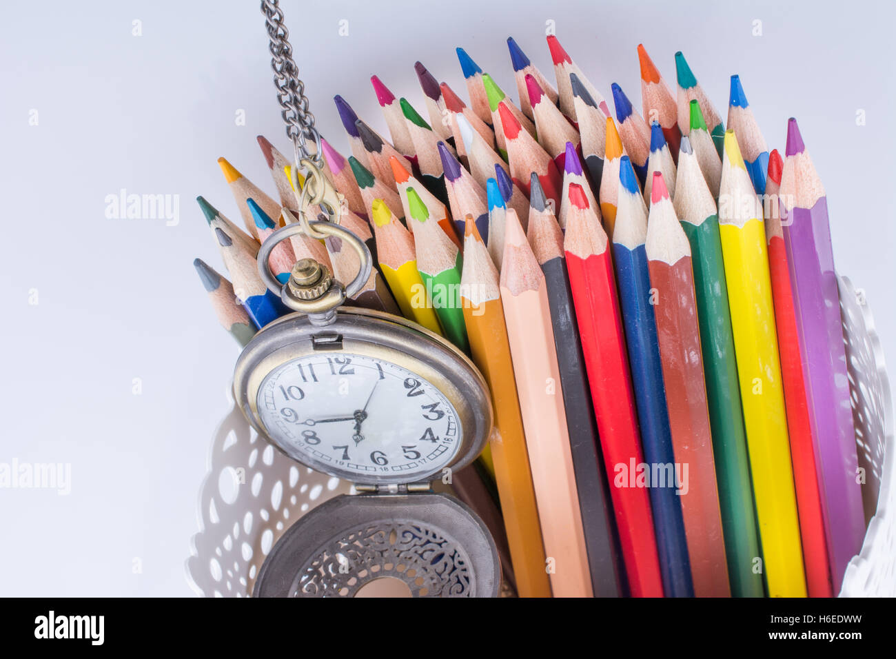 Retro style classic pocket watch and color pencils on white background ...