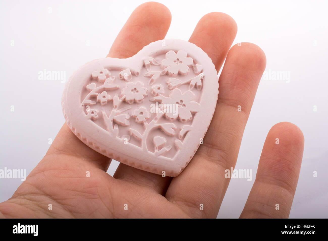 Heart shaped stone object held in hand on white background Stock Photo ...