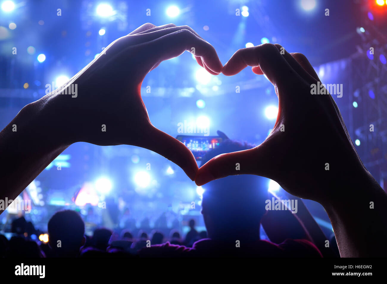 Silhouette of a heart shaped hands and crowd of Audience at live ...