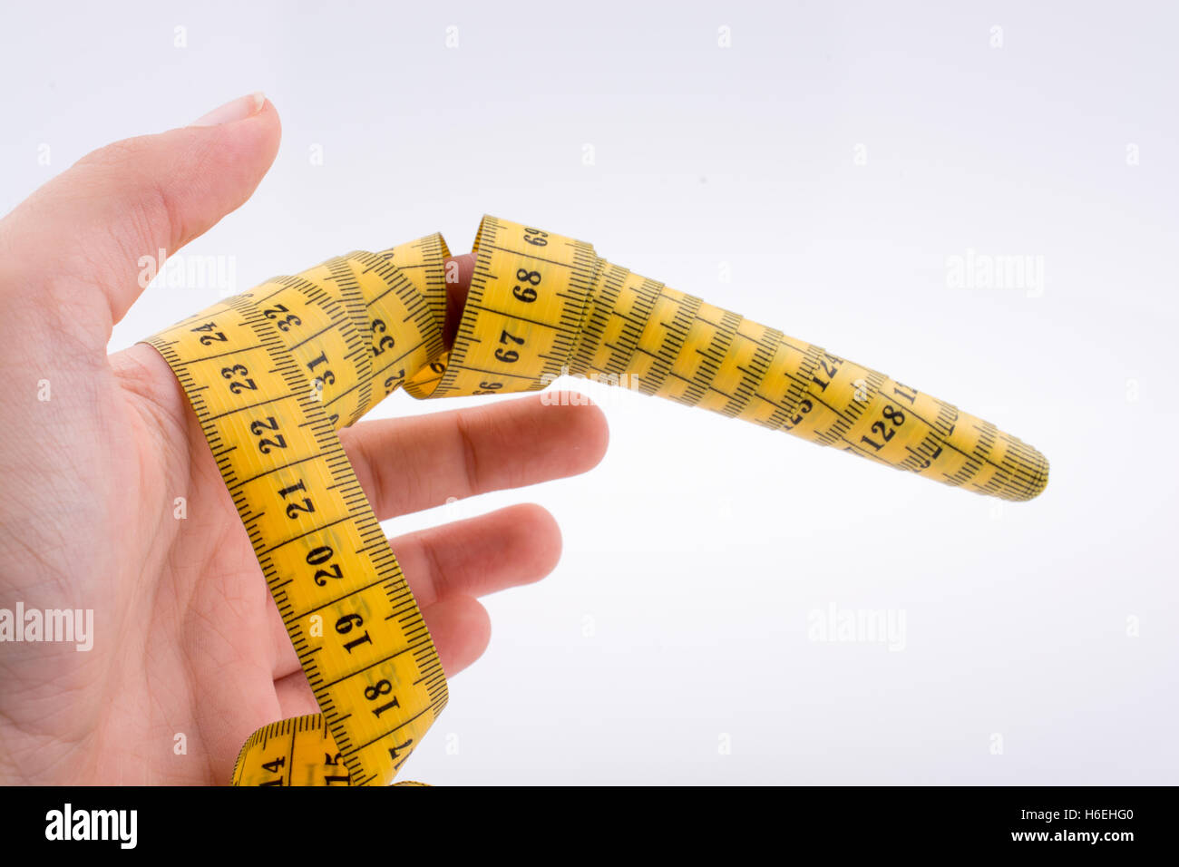 Hand holding a yellow color measuring tape on a white background Stock ...