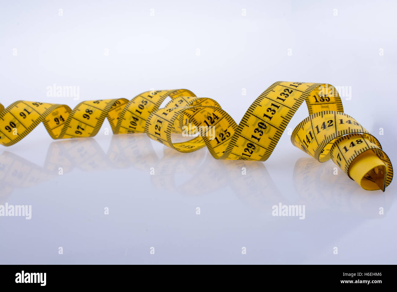 Yellow color measuring tape on a white background Stock Photo - Alamy