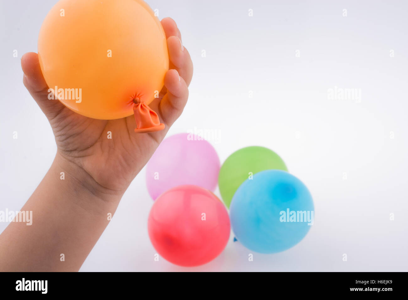 Hand holding a Colorful small balloon with colorful balloons on the ...