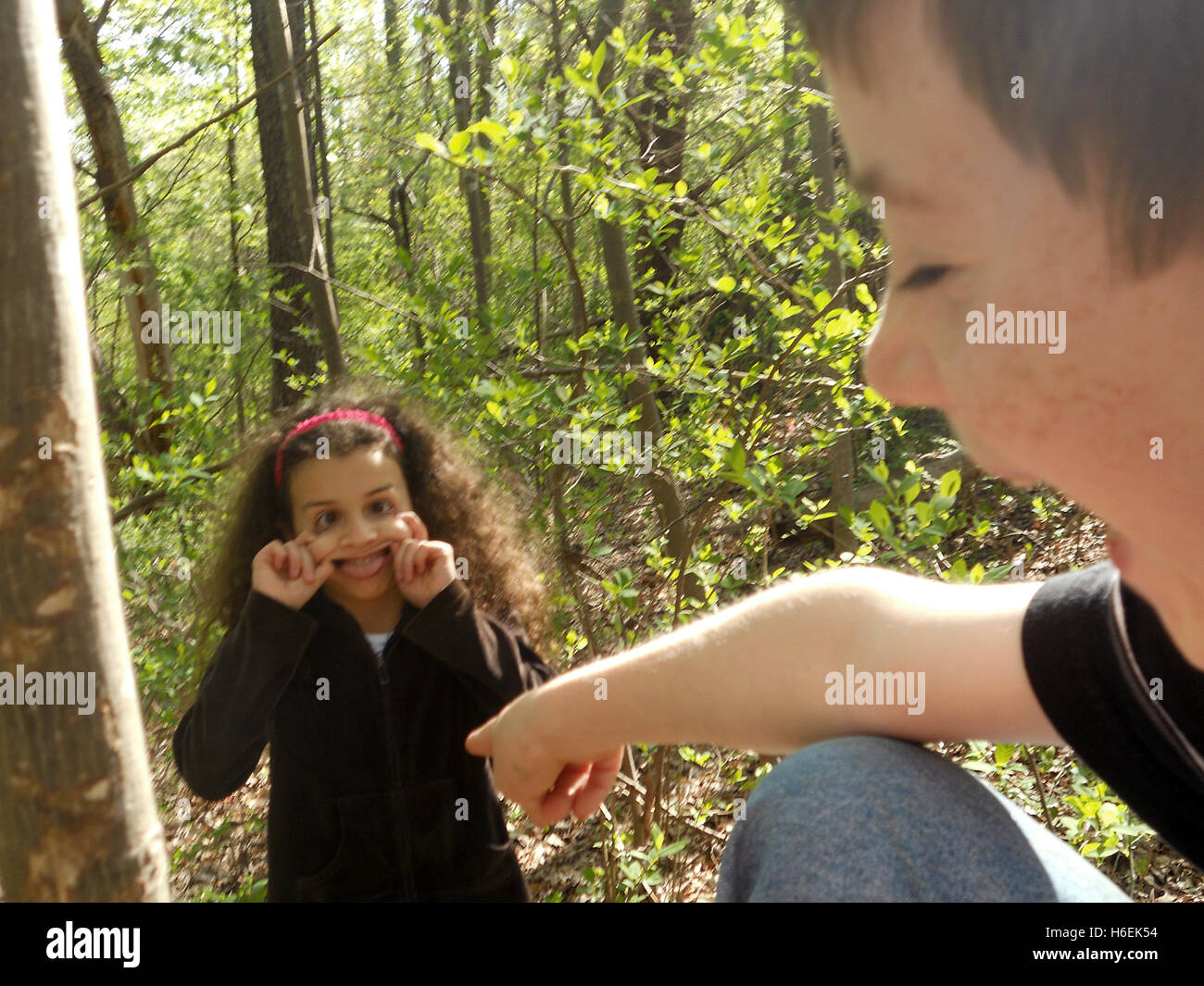 Kids at play outdoors. Little boy laughing and pointing at little girl ...