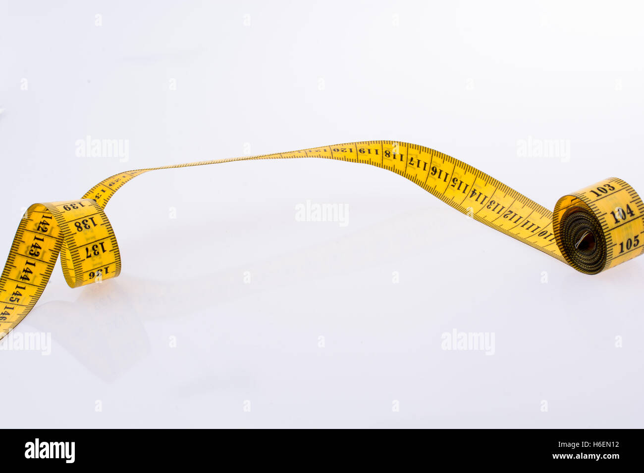 Yellow color measuring tape on a white background Stock Photo - Alamy