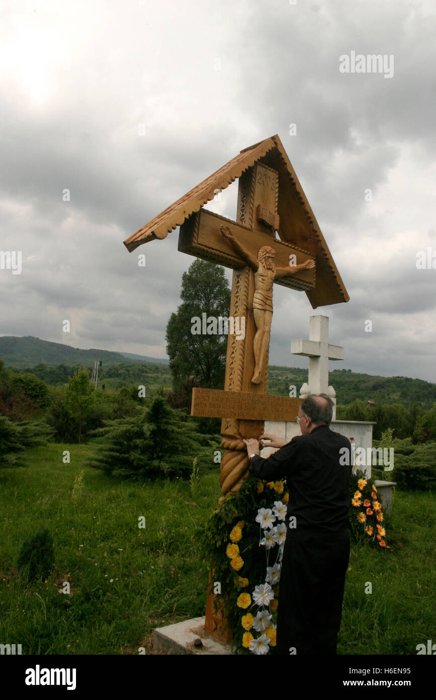 Man praying at wooden crucifix raised in memory of victims of communism ...