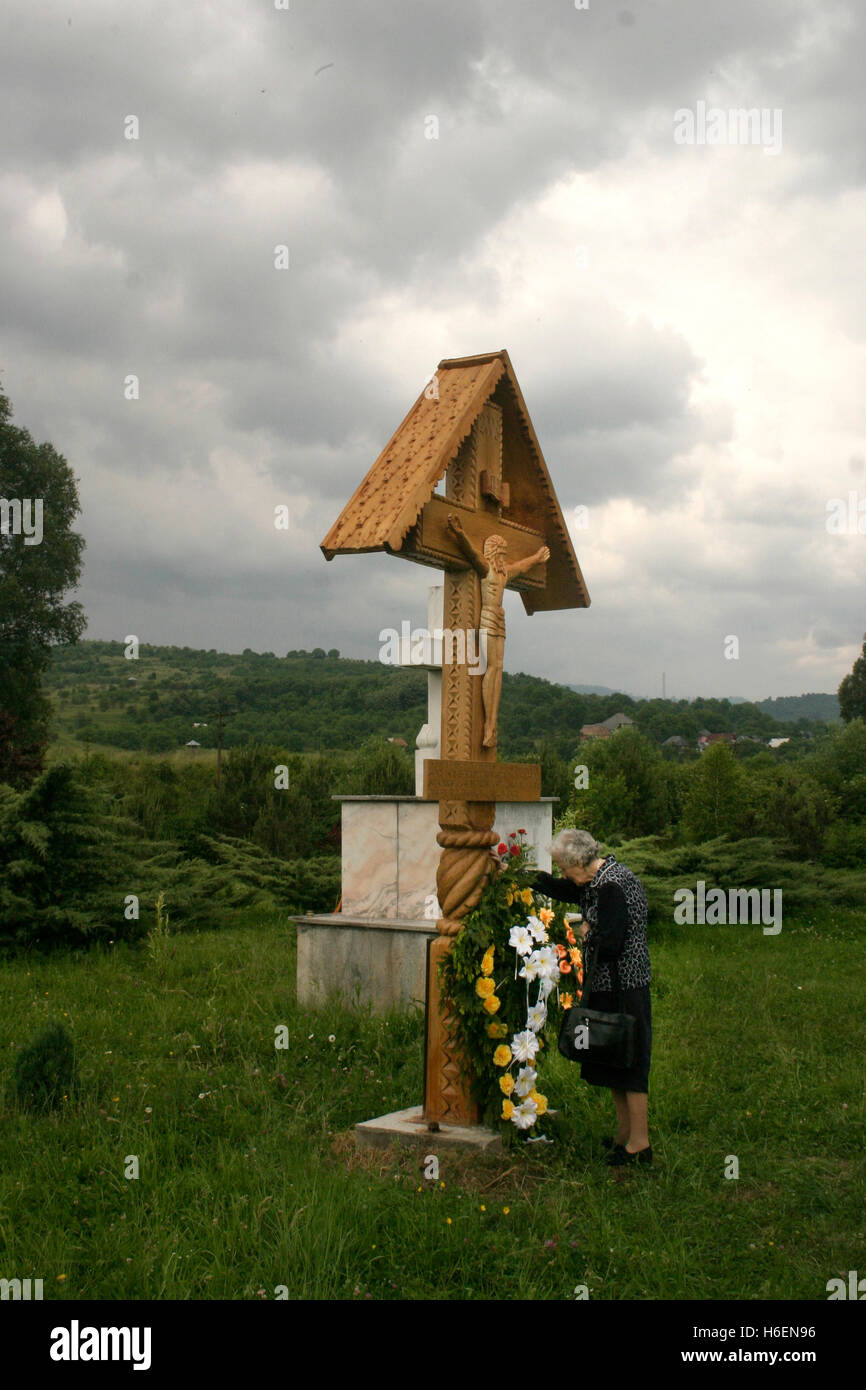 Old lady praying at wooden crucifix raised in memory of victims of ...