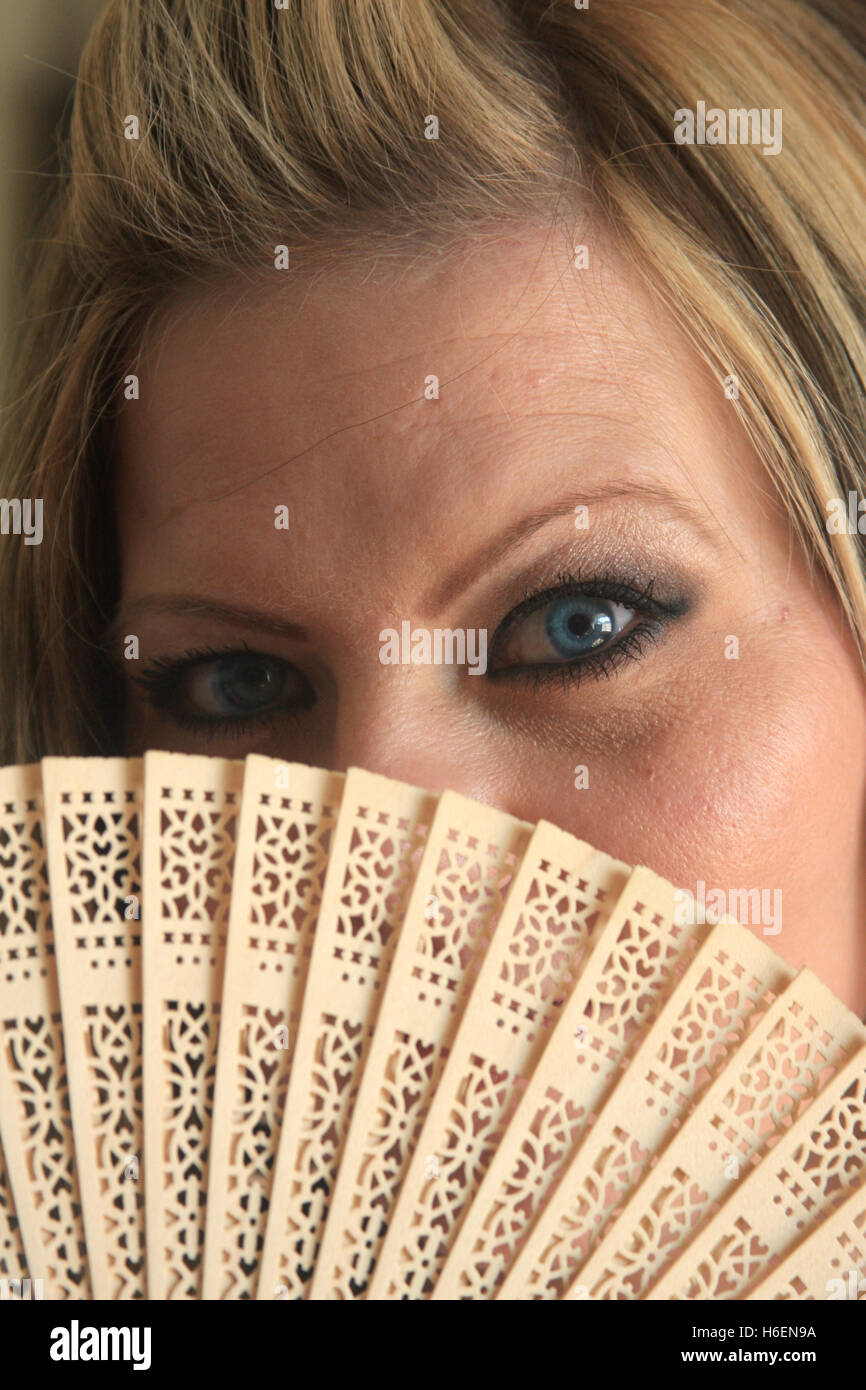 Portrait of young woman with blue eyes, behind hand fan Stock Photo - Alamy