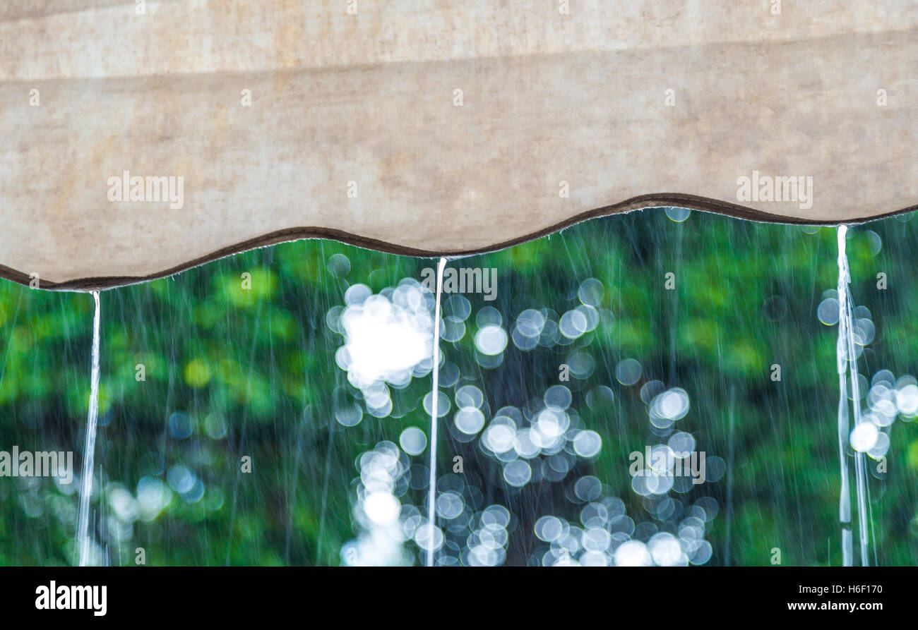 Close focus on rain flowing down from brown canvas roof. Outside is ...