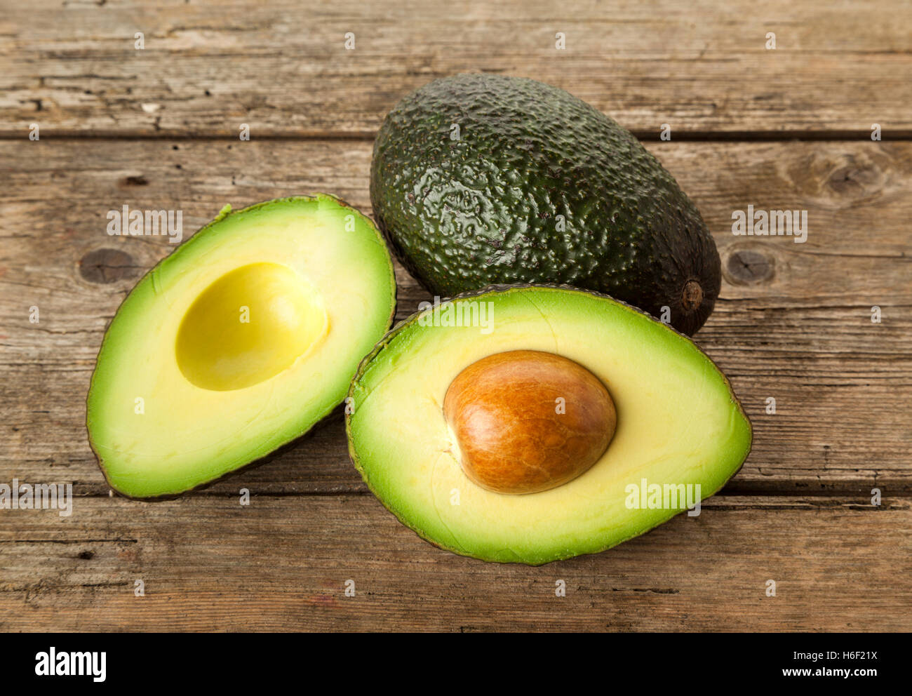 Whole and halved avocados on rustic wooden table, top view Stock Photo ...