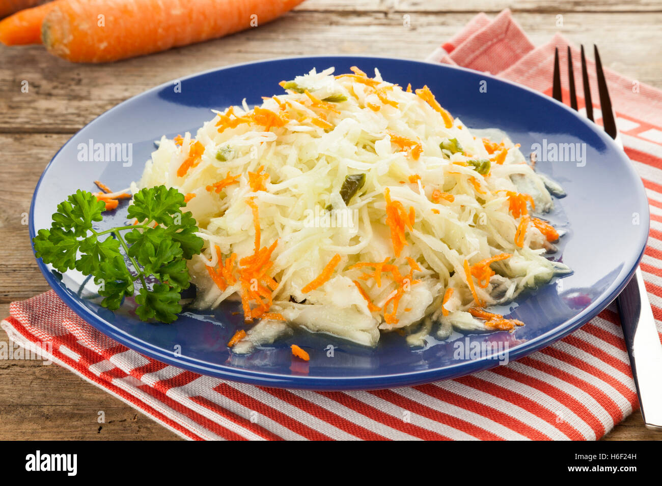 Coleslaw salad with carrots and parsley on blue plate with napkin and ...