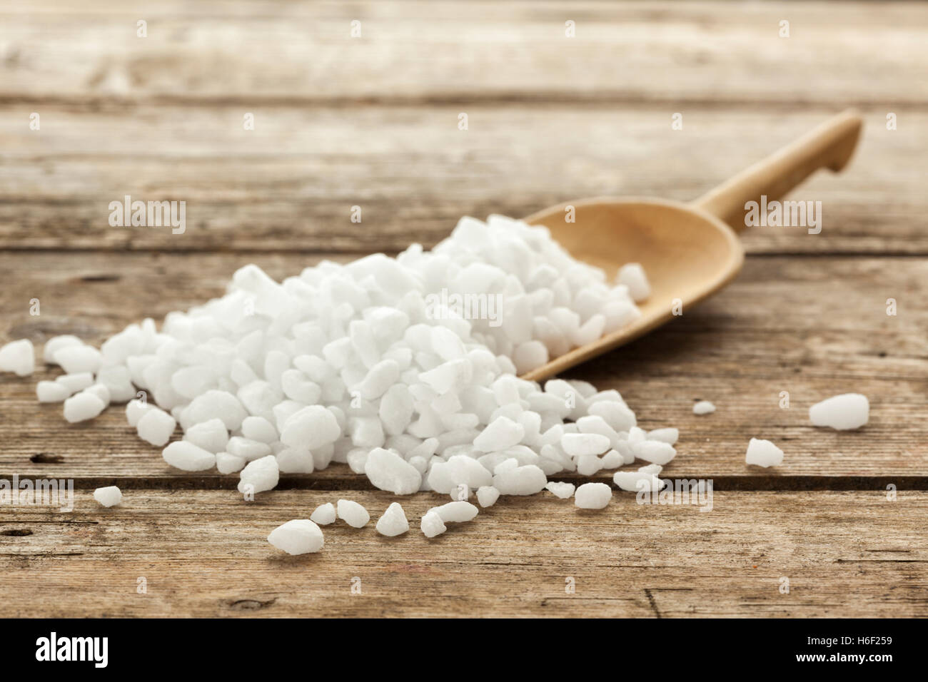 Coarse salt with wooden shovel on rustic table, closeup, shallow depth ...