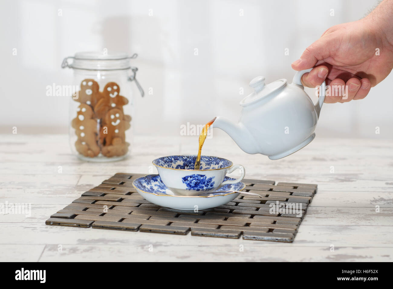 Pouring a cup of tea with cookie jar of gingerbread in the background ...