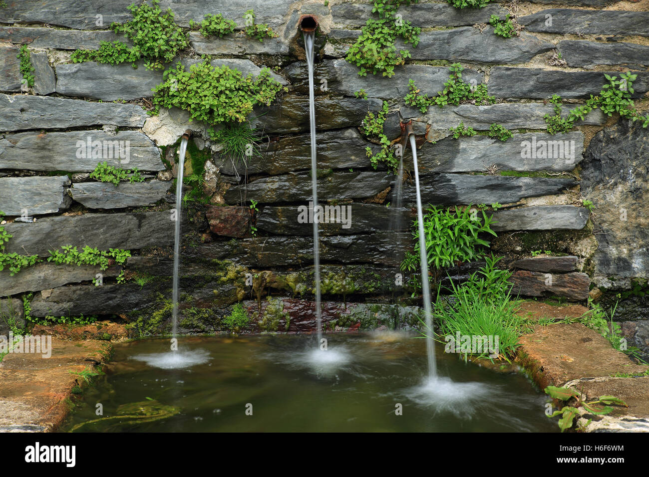 stone fountain with three jets of water falling Stock Photo - Alamy
