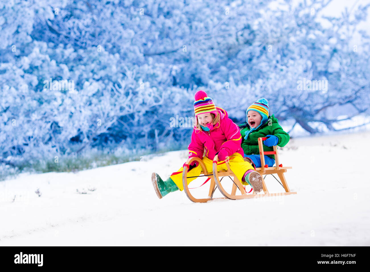 Little girl and boy enjoy a sleigh ride. Child sledding. Toddler kid ...