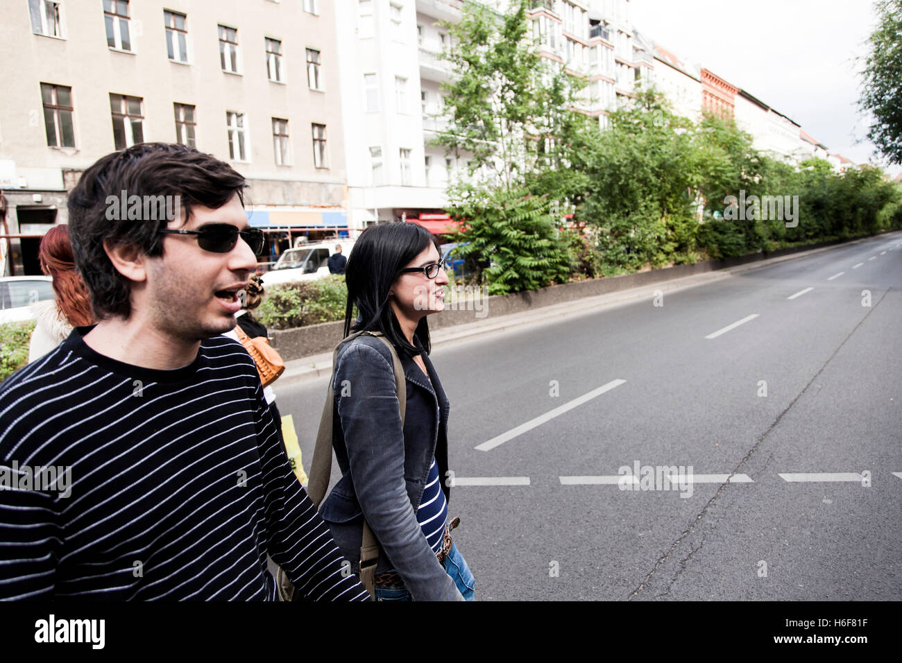 A couple in their early thirties crossing the street while having a ...