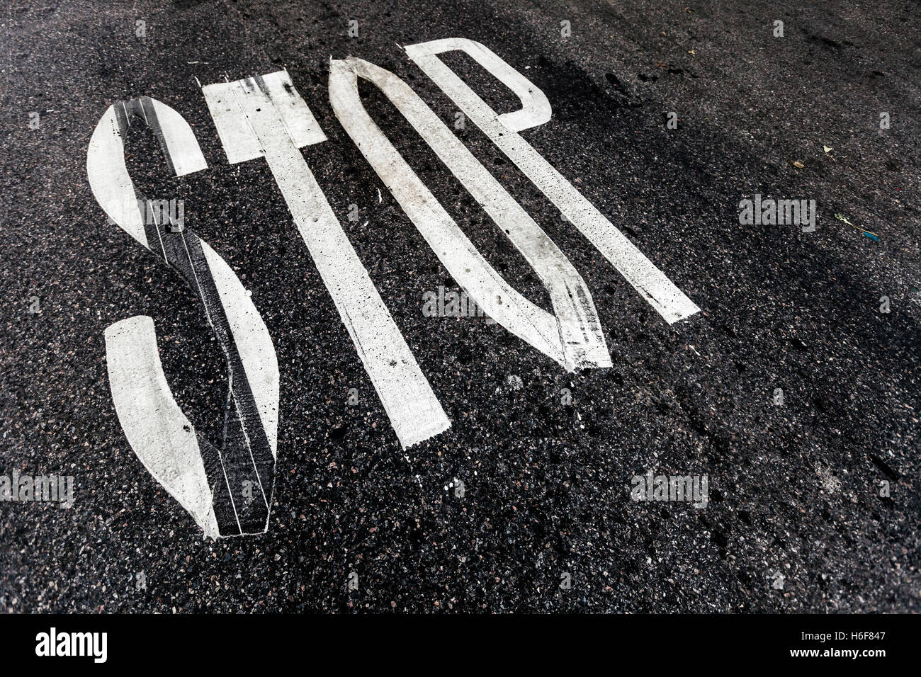 Wide angle view of a white painted "stop" side on a street's asphalt ...