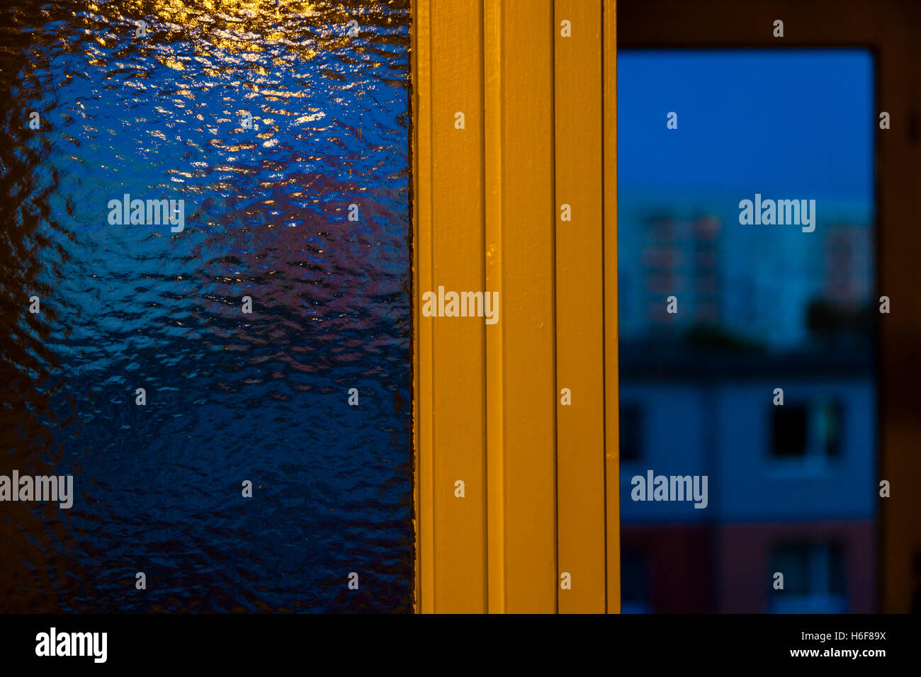 Tungsten lighting reflecting off a bumpy window, with another window in ...