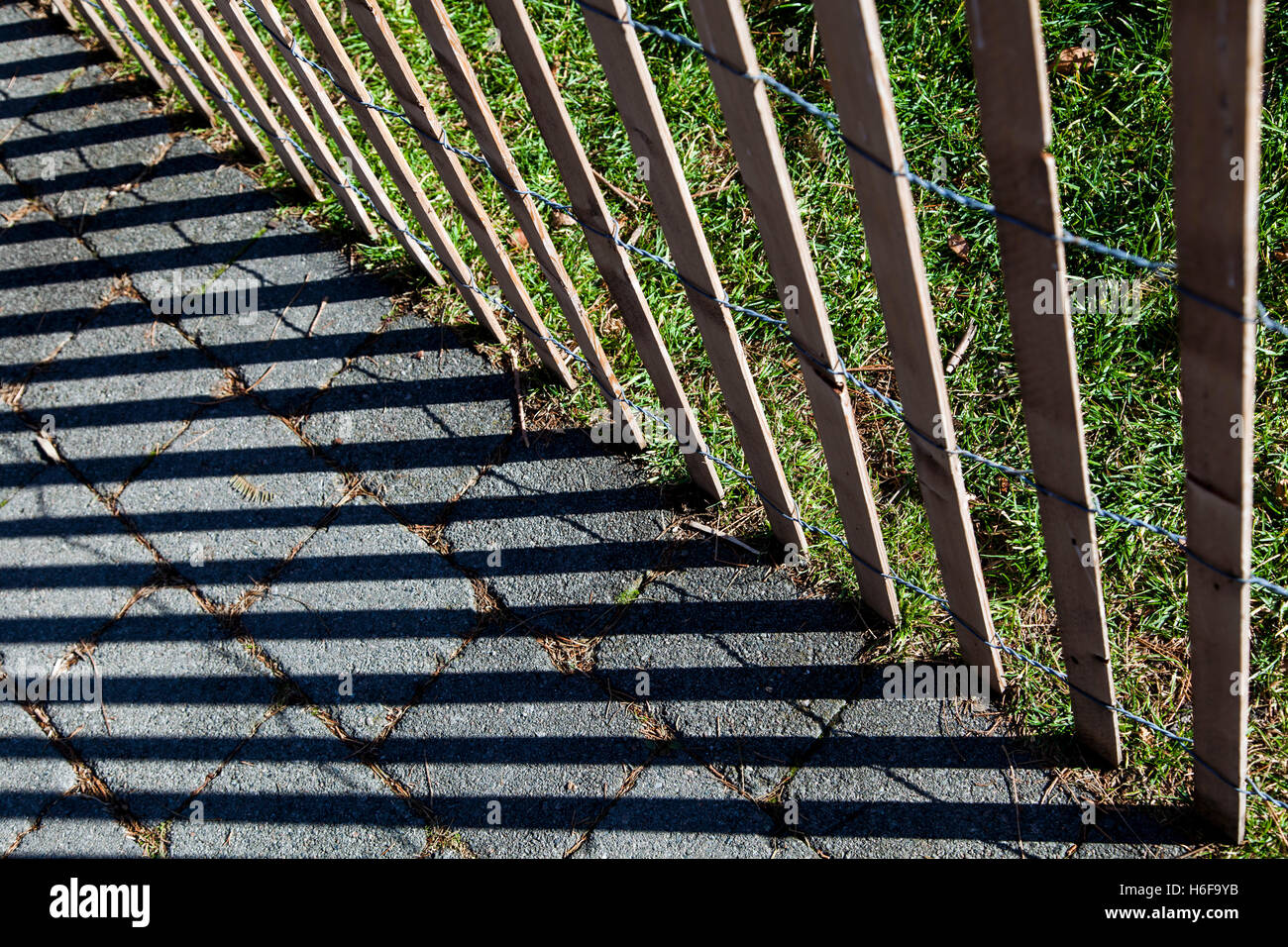 Fence made of thin wooden beams, bordering between stone tile floor and ...