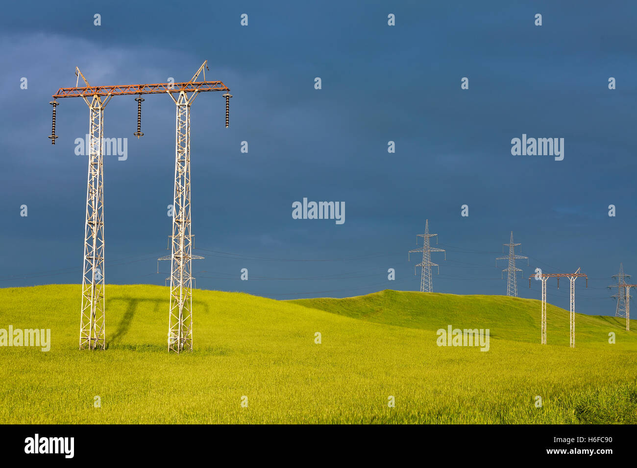 Power lines in green field Stock Photo - Alamy
