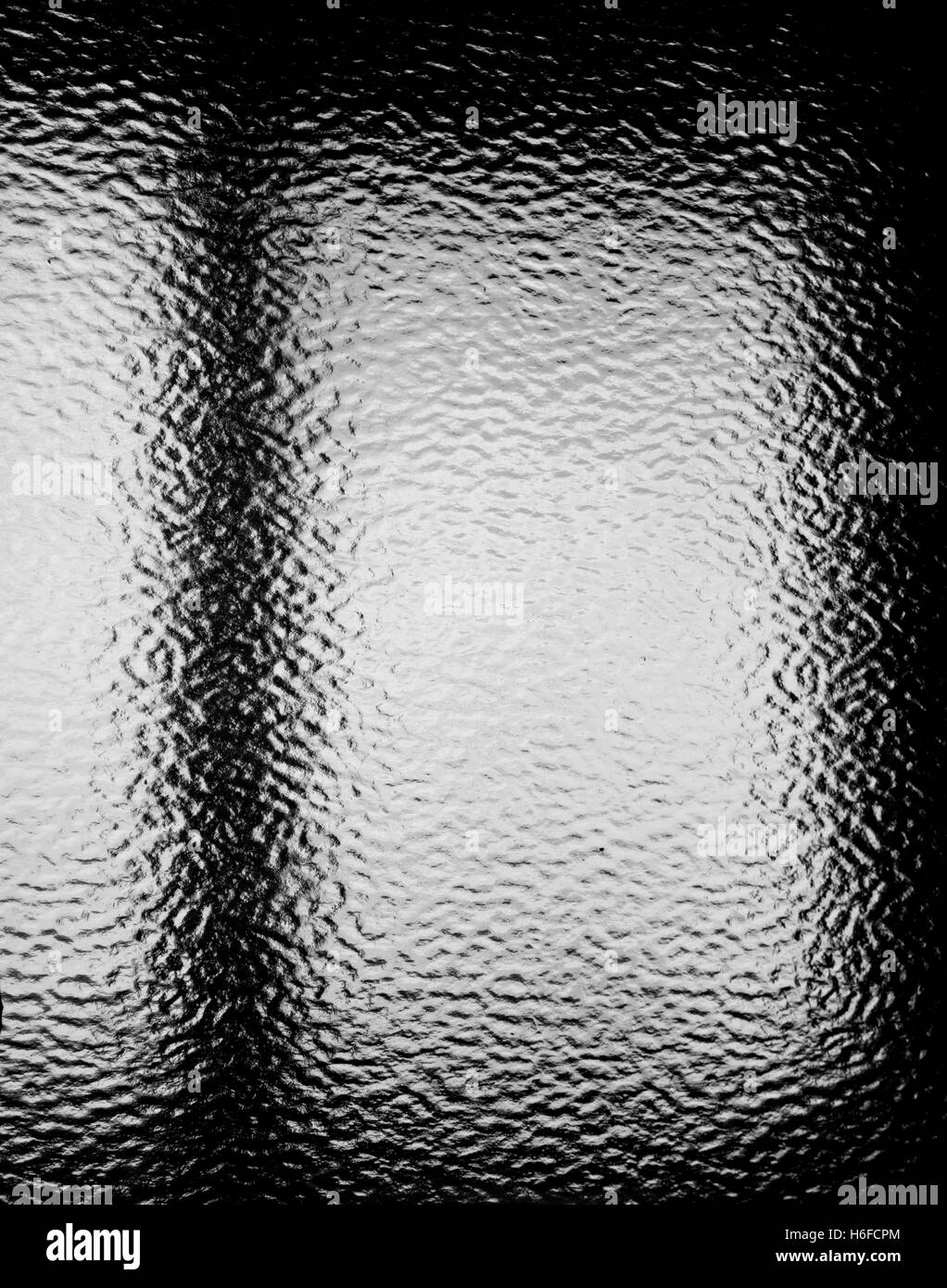 The silhouette of a window as seen through a glass with a bumpy surface ...