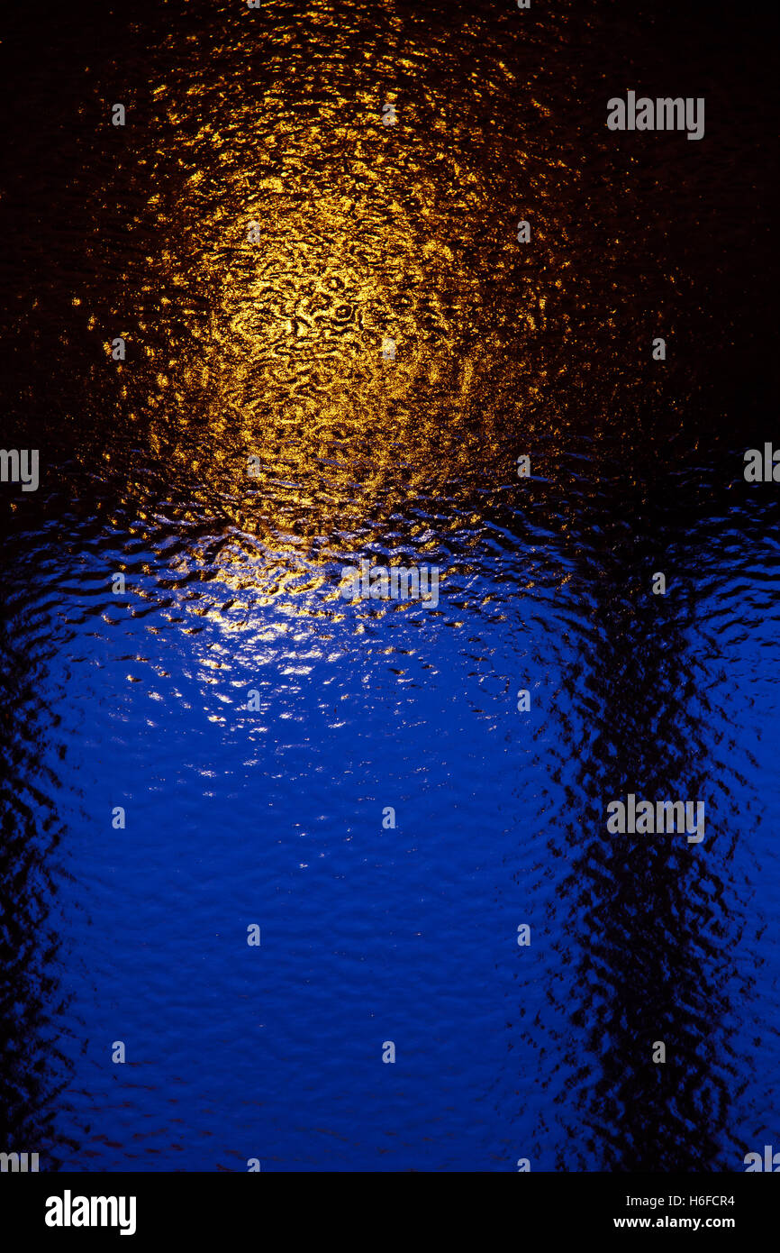 Abstract view of tungsten lighting reflecting off of textured glass ...