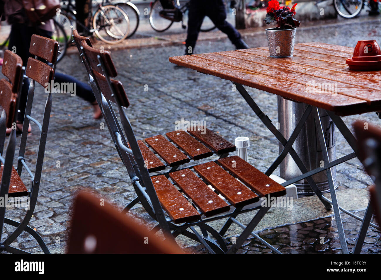 Wet tables and chairs of a cafe, wet from the pouring rain in Berlin ...