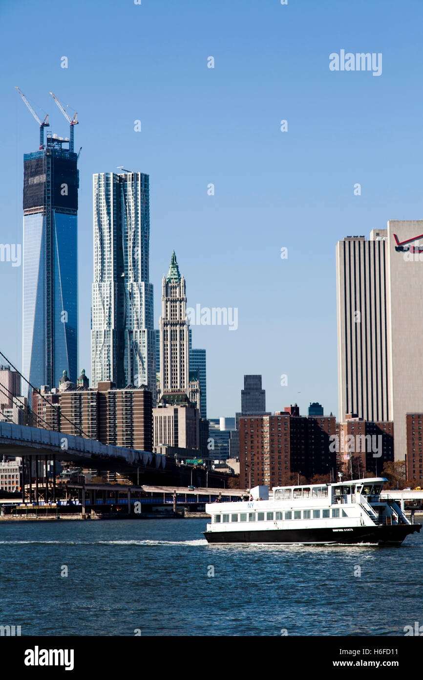 Ferry sailing on the East River with the Brooklyn Bridge stretching ...