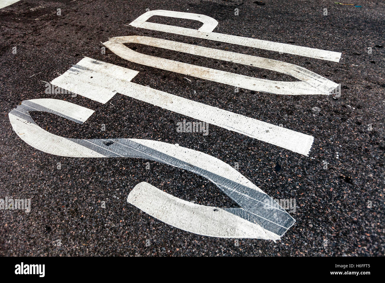 Wide angle view of a white painted "stop" side on a street's asphalt ...