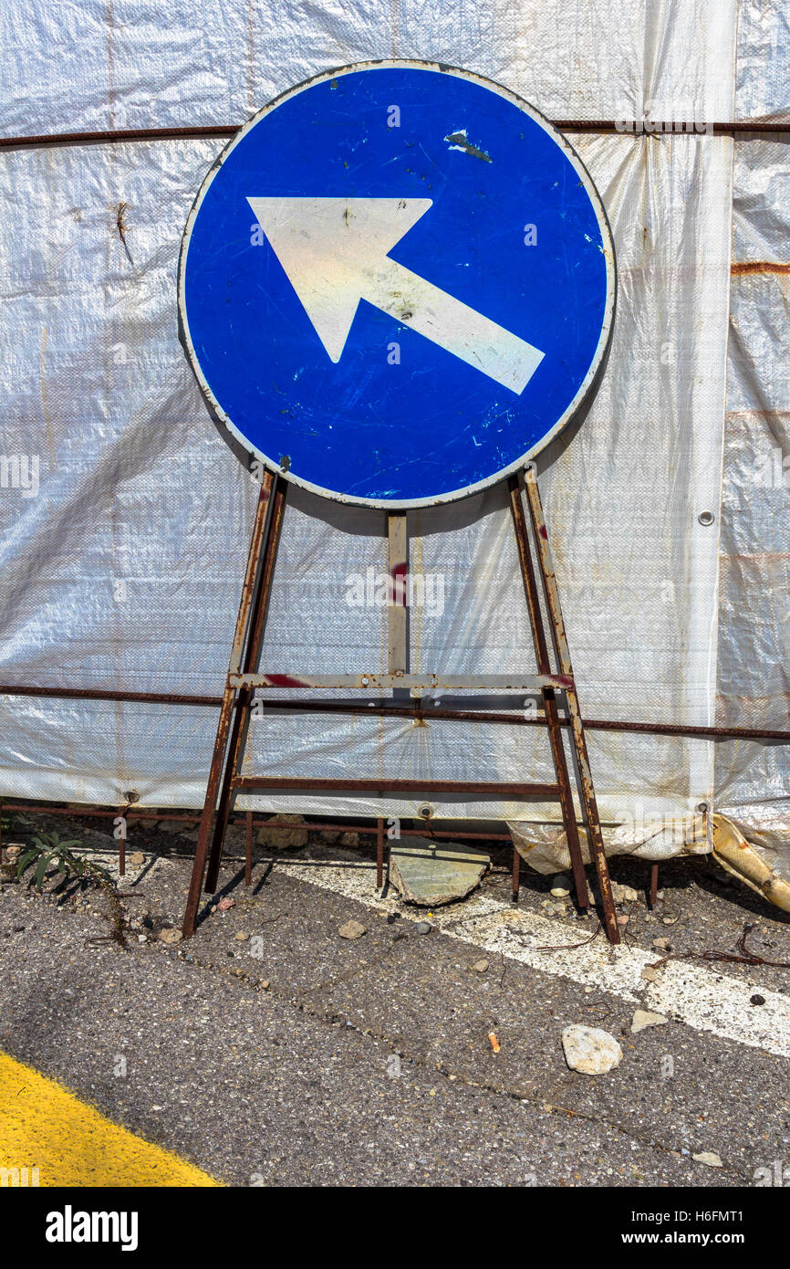 Old mandatory direction sign with scratches and dents in construction ...
