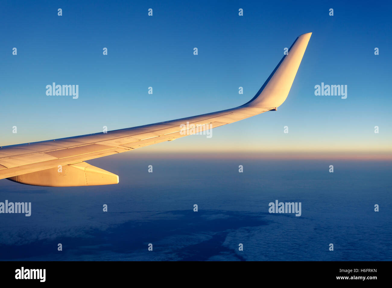 Passenger aircraft wing against clear blue sky, purple split toning ...