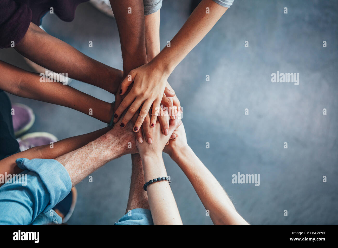 Close up top view of young people putting their hands together. Friends with stack of hands ...