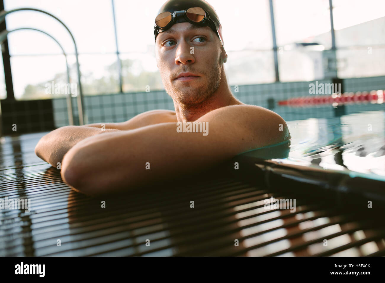 Shot of professional male swimmer resting on the edge of swimming pool ...