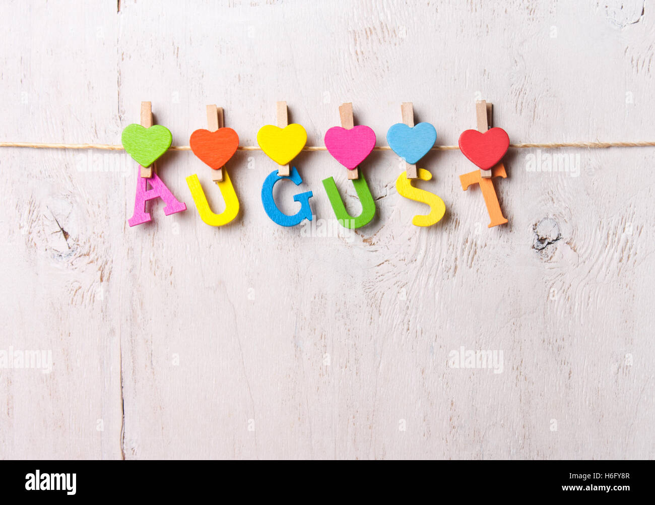 the word "august" letters on a wooden clothespins on a white background ...