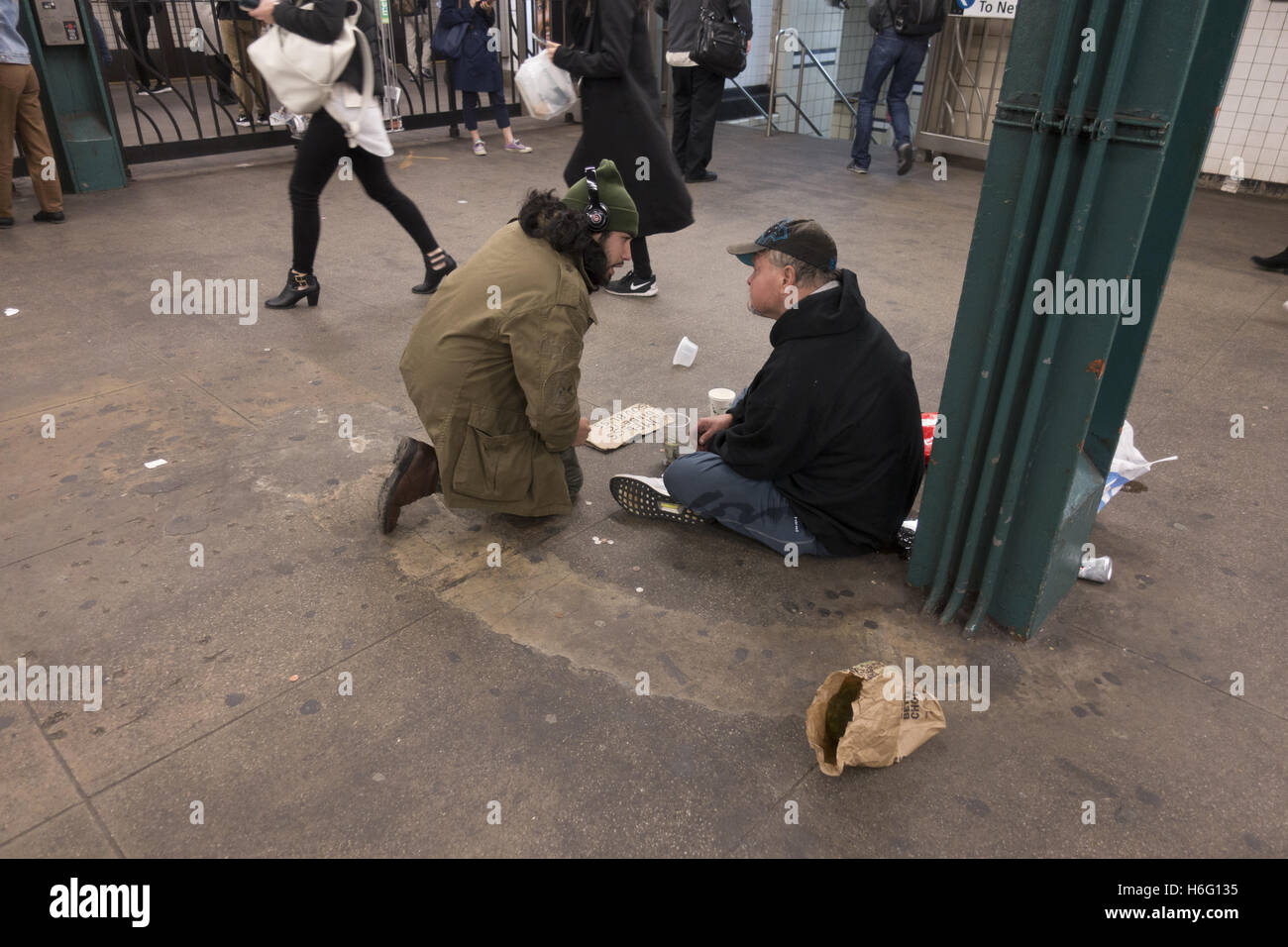 Younger man reaches out to an older homeless man begging in a subway ...