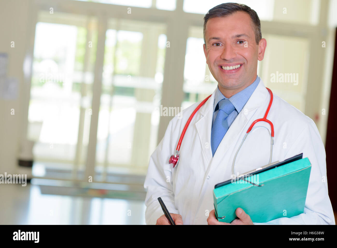 Smiling doctor holding files Stock Photo - Alamy