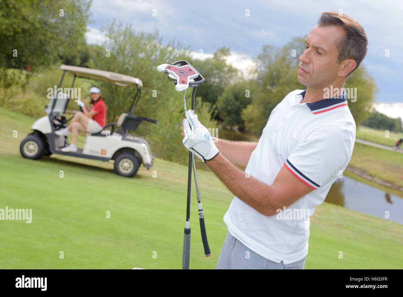Man comparing golf clubs Stock Photo - Alamy