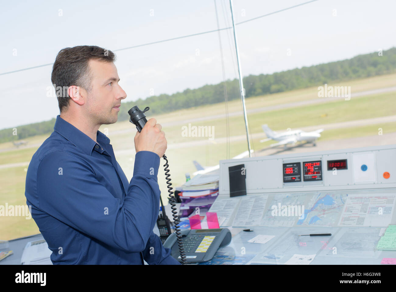 Man in control tower talking into microphone Stock Photo - Alamy