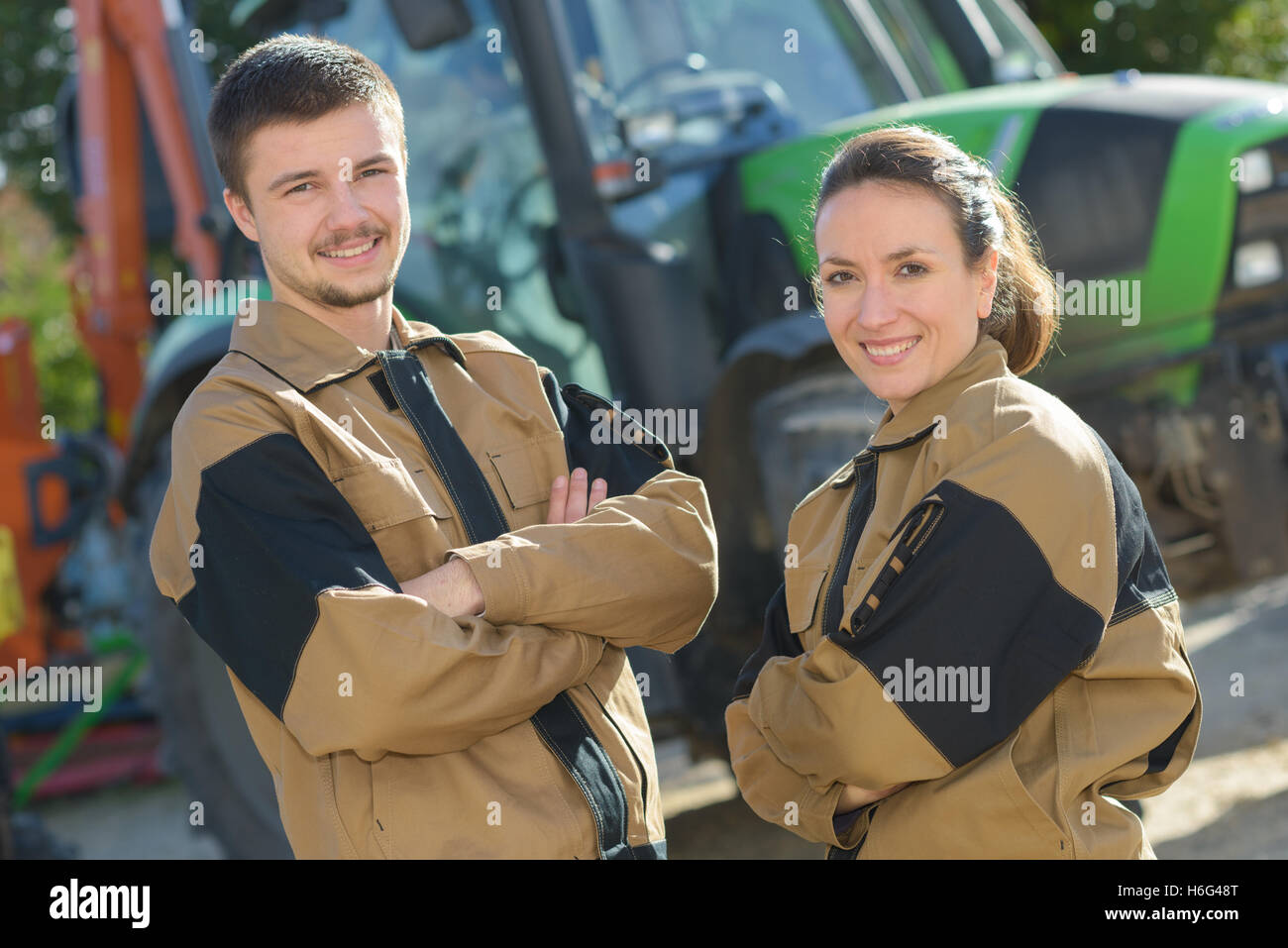 couple standing in front of tractor Stock Photo - Alamy
