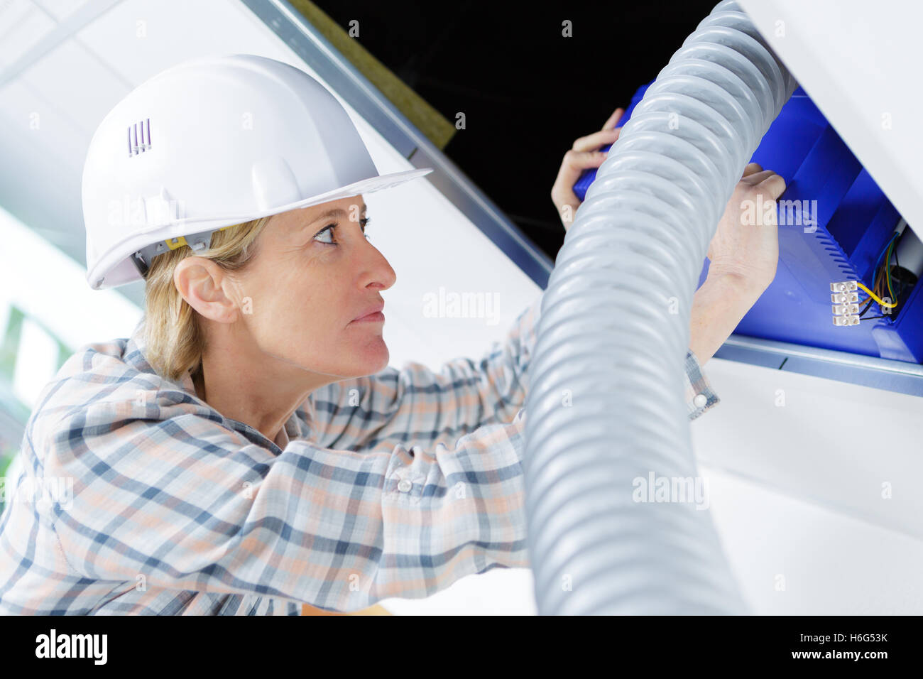 female worker fitting ventilation system in buildings ceiling Stock ...