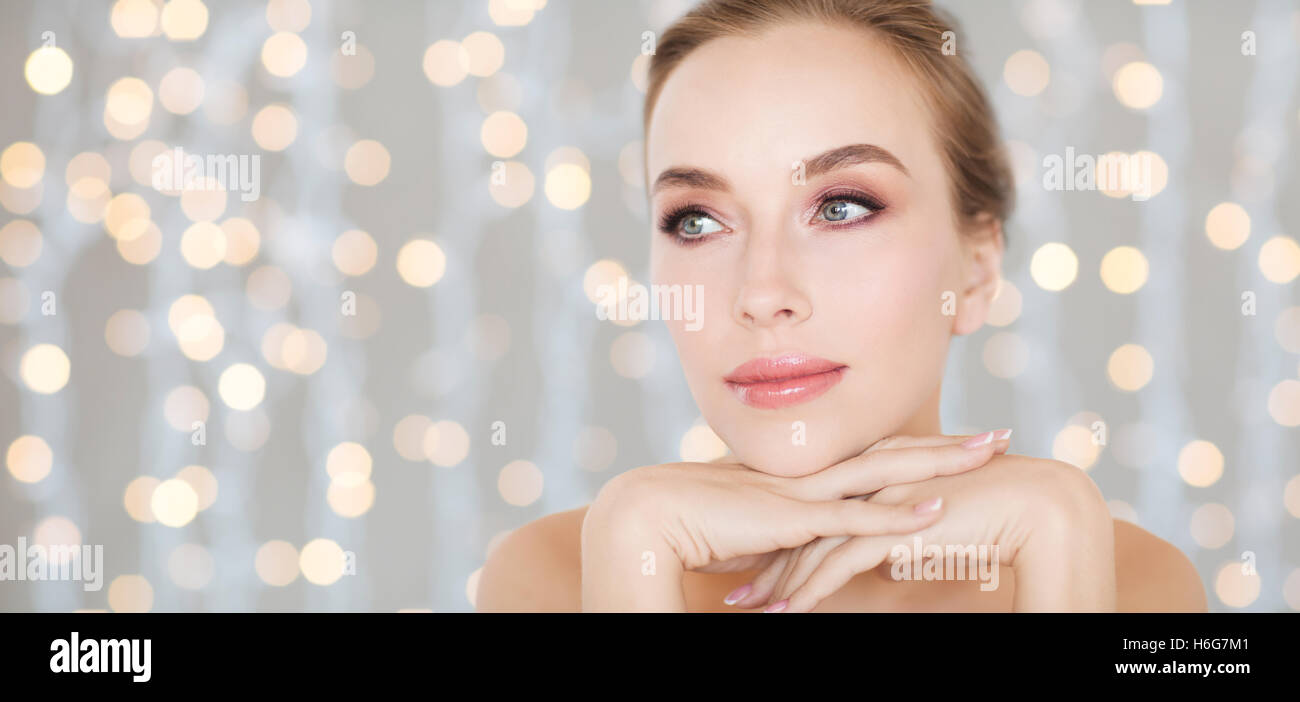 beautiful young woman face and hands over lights Stock Photo - Alamy
