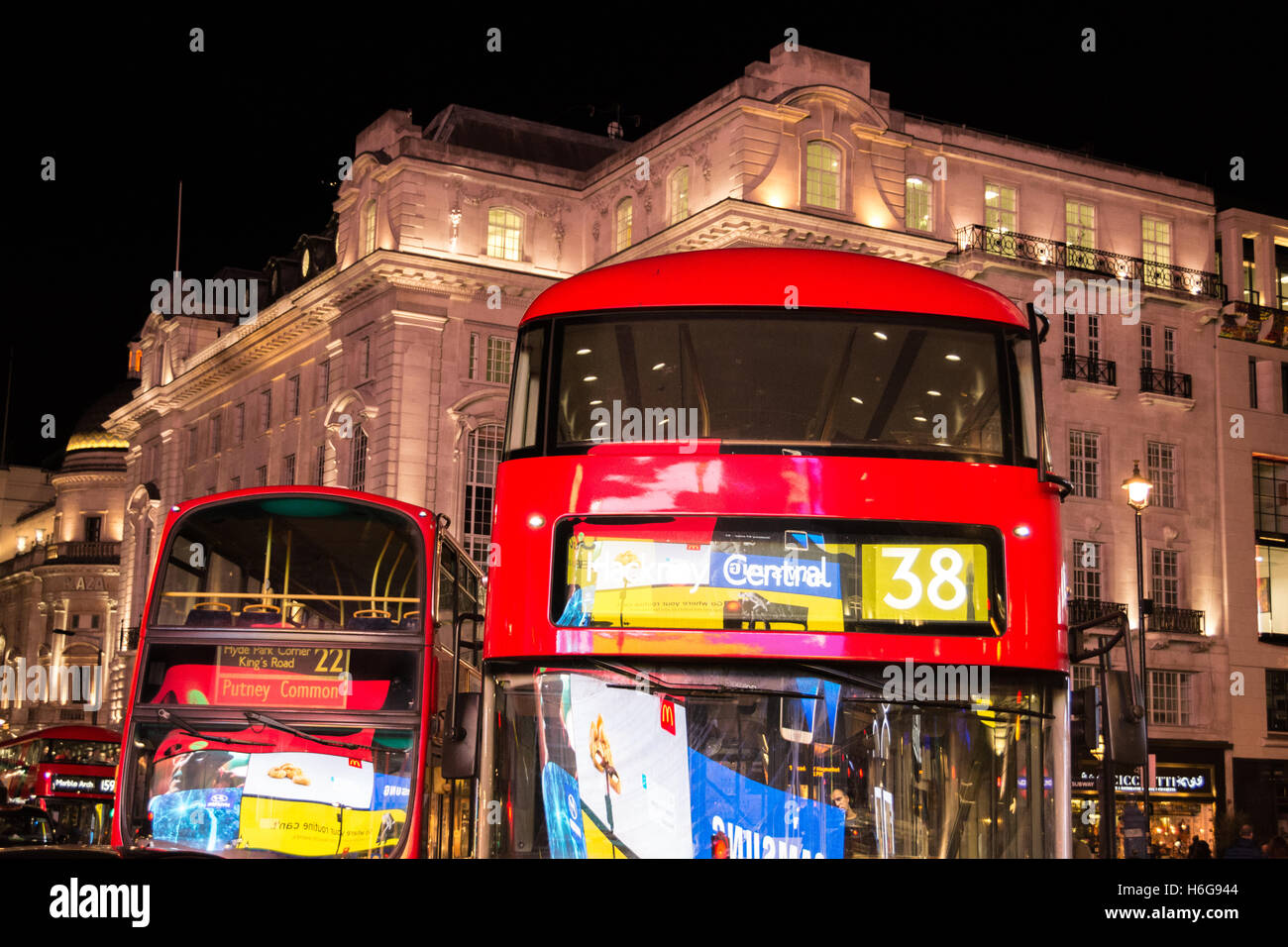 Night-time buses pass through a brightly lit and illuminated Piccadilly ...