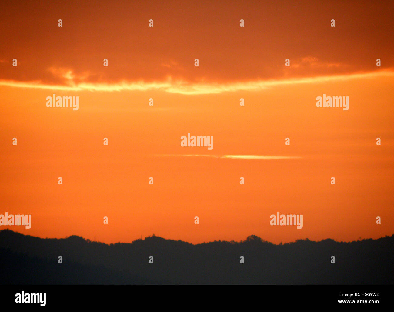 Orange gradation of sunset cloudy sky over the silhouette of mountain ...